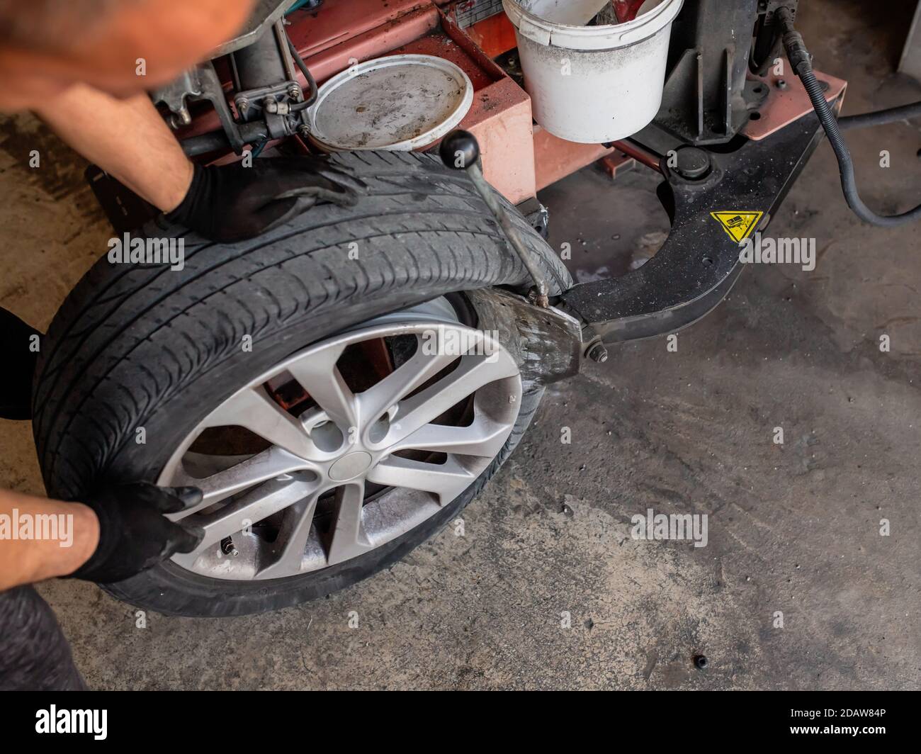 Mechanic with pneumatic wrench unscrews the wheel. Male professional ...