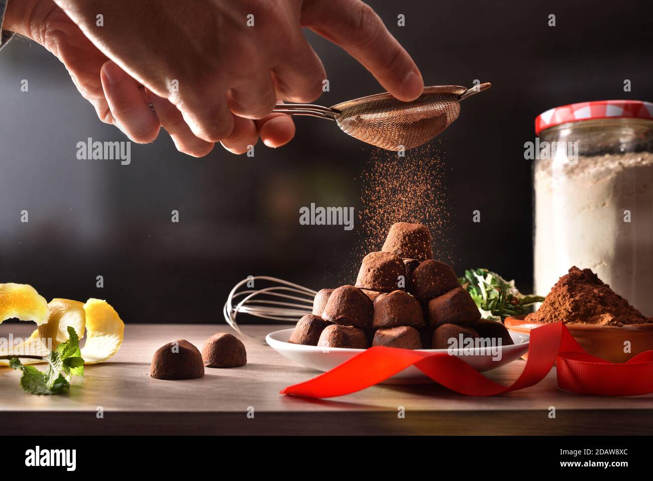 Hands pouring cocoa powder on pile of freshly made chocolate truffles ...