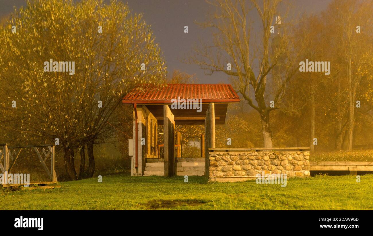 autumn fog landscape from the park, illuminated trees and buildings in ...