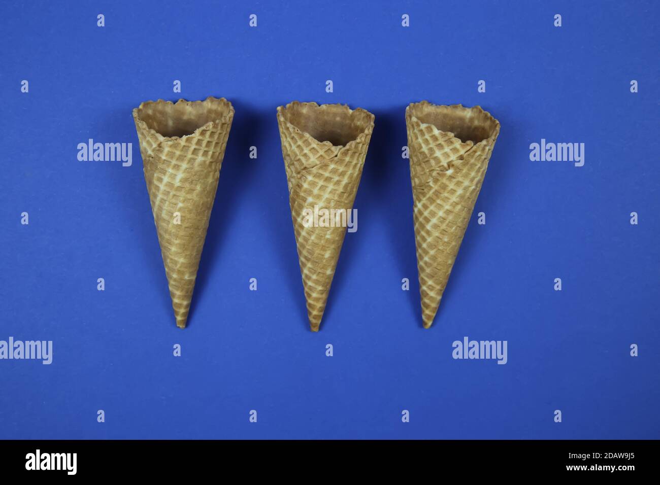 Close up of three isolated ice cream waffle cones on blue blank ...