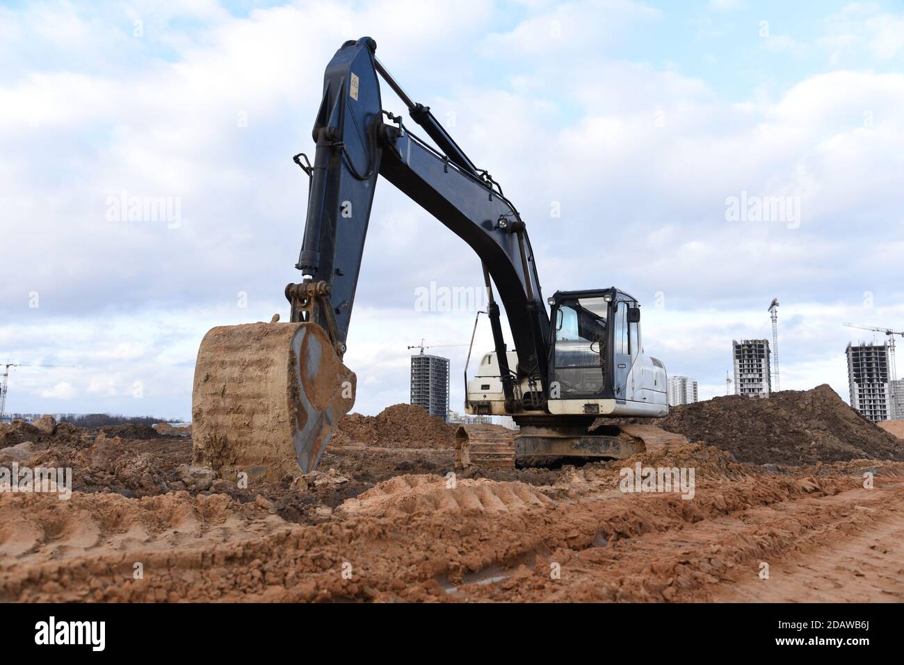 Black and white excavator during earthworks at construction site ...