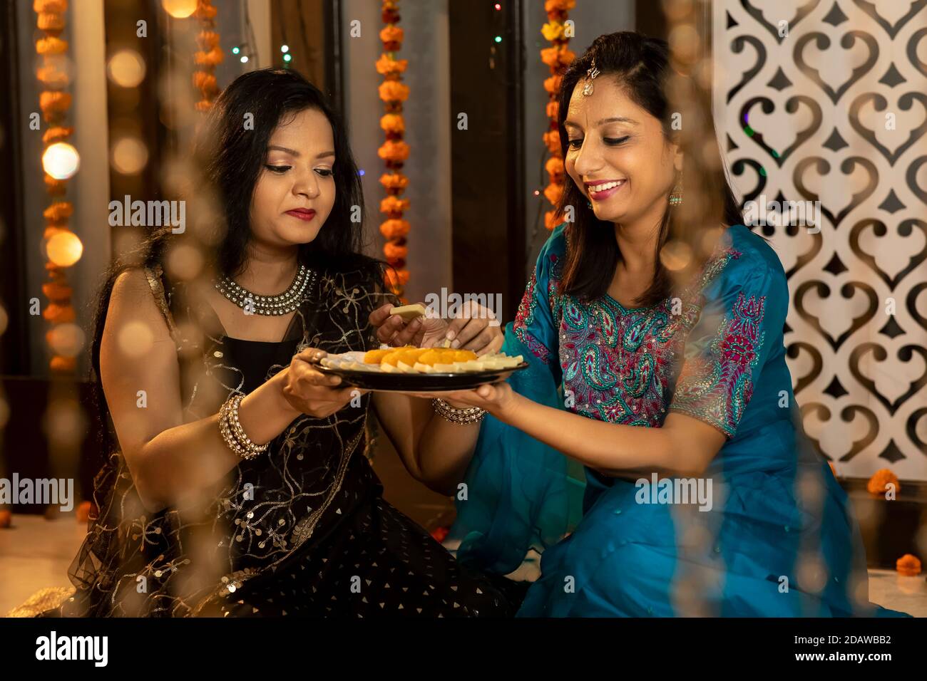 Portrait of two Indian woman sharing sweets on the festive occasion of ...
