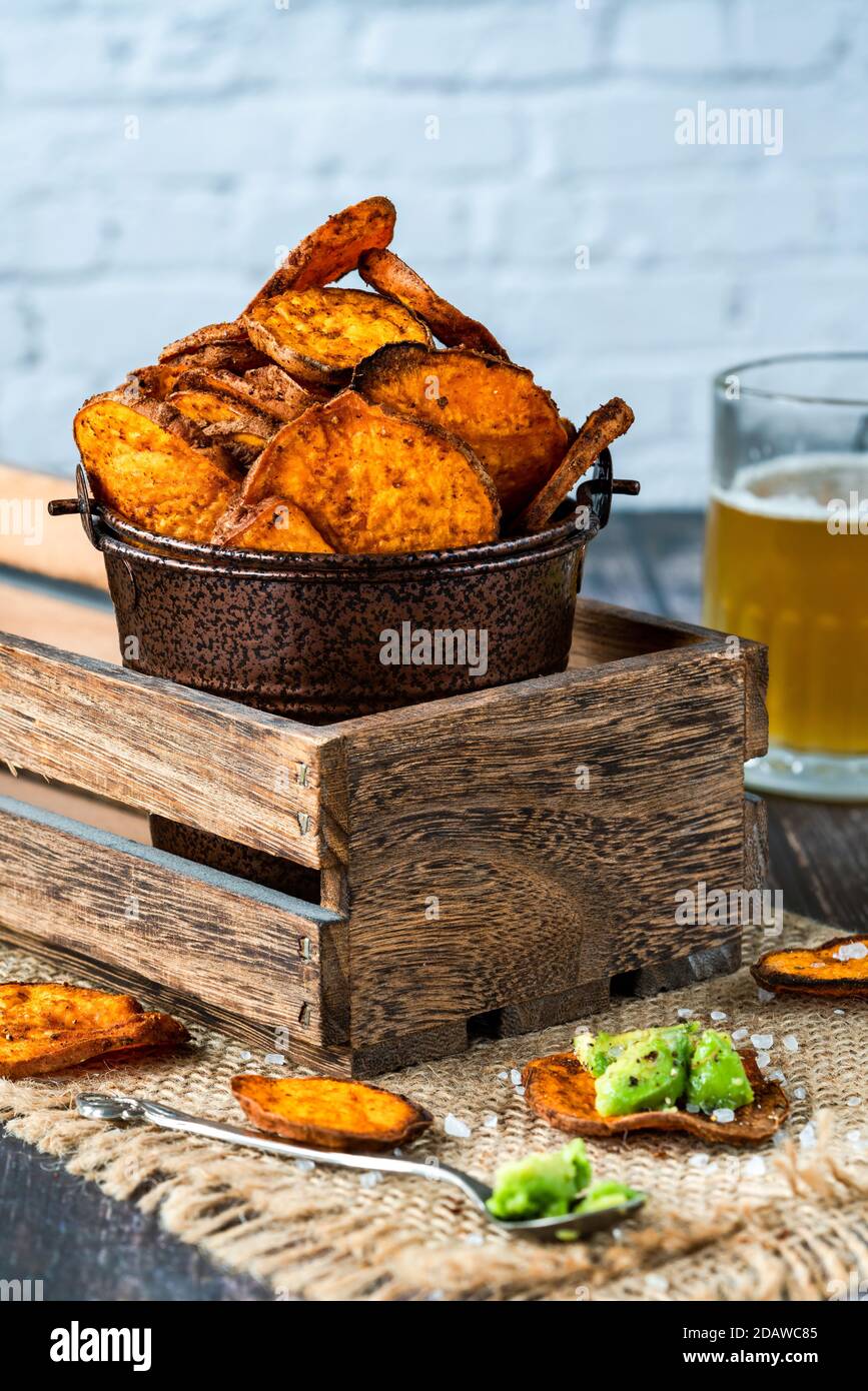 Homemade spiced sweet potato chips with smashed avocado Stock Photo - Alamy