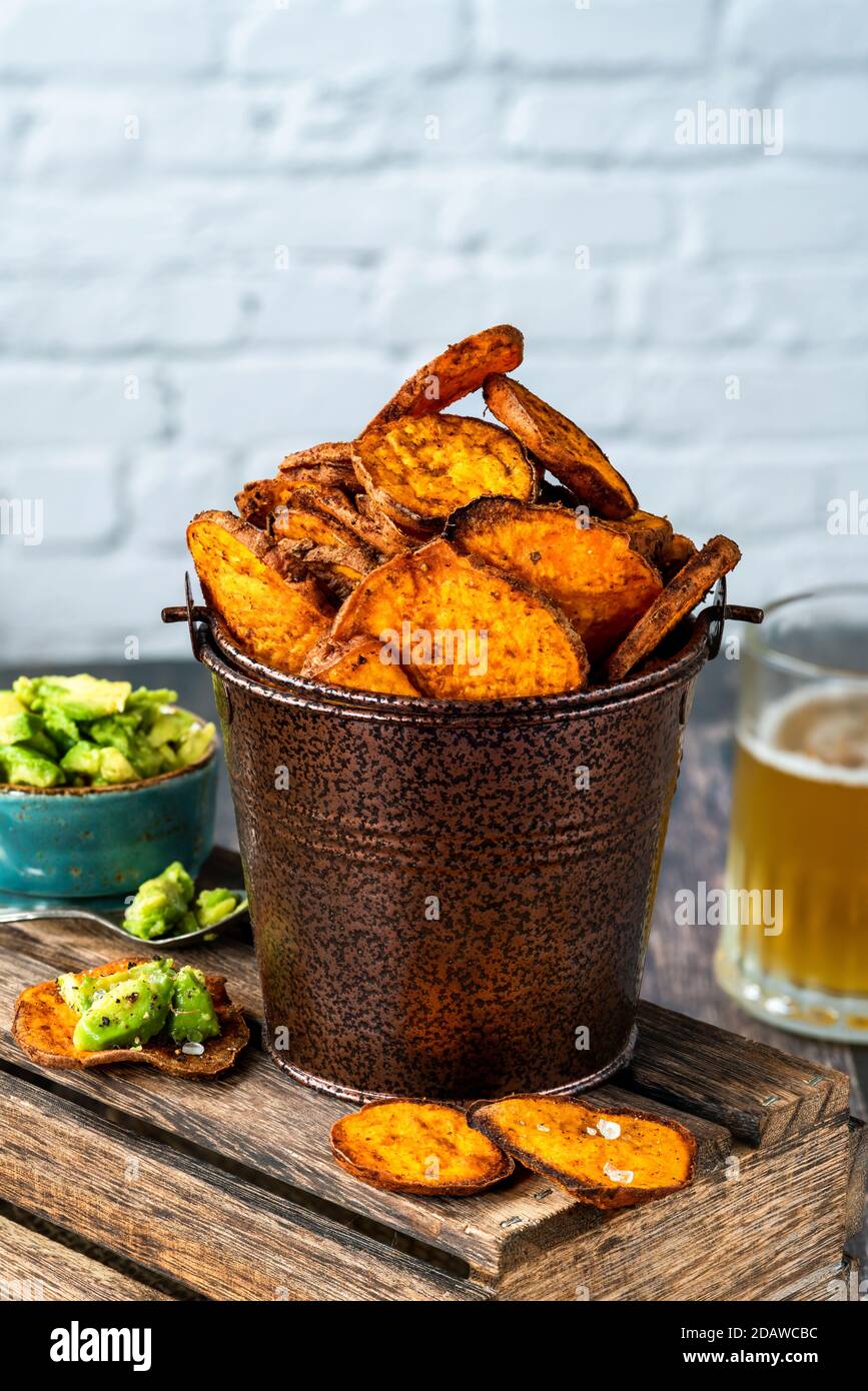 Homemade spiced sweet potato chips with smashed avocado Stock Photo - Alamy