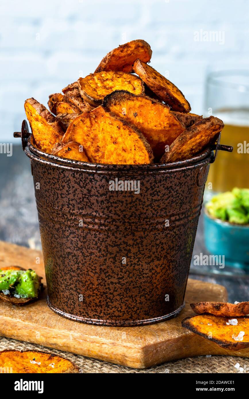Homemade spiced sweet potato chips with smashed avocado Stock Photo - Alamy