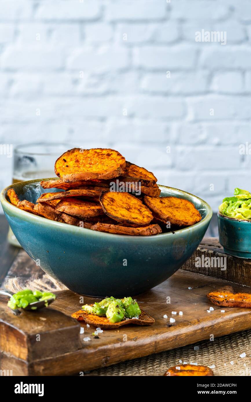 Homemade spiced sweet potato chips with smashed avocado Stock Photo - Alamy