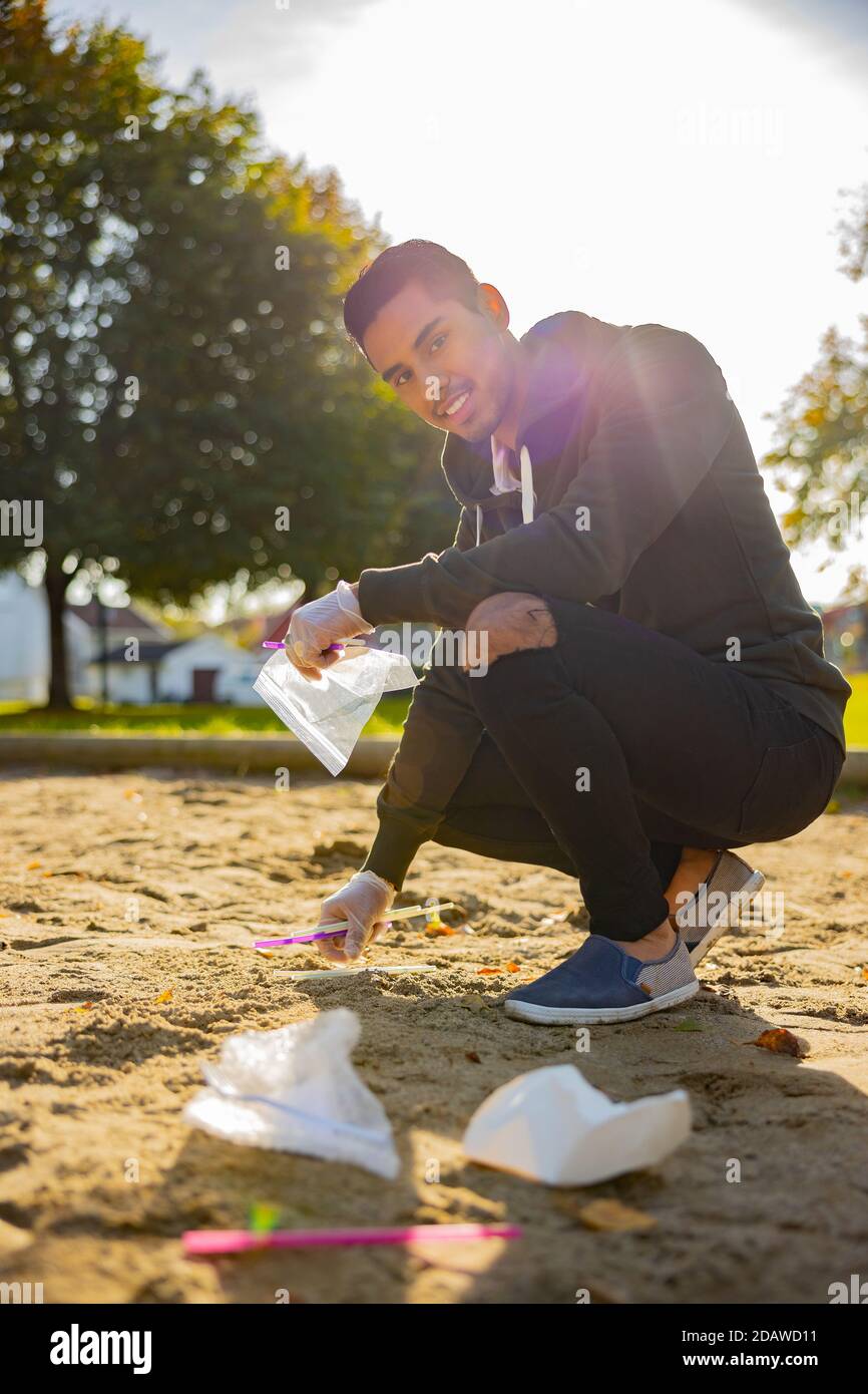 Back lit of smiling man cleaning garbage on sand at park Stock Photo ...