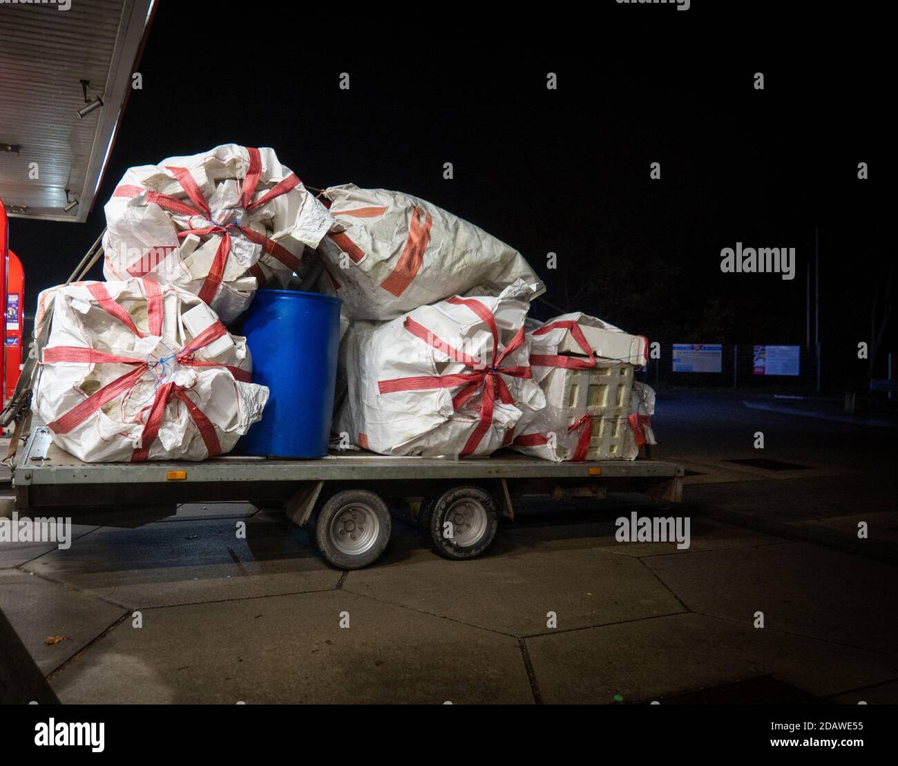 on a car trailer is a large load of white waste bags plastic garbage ...