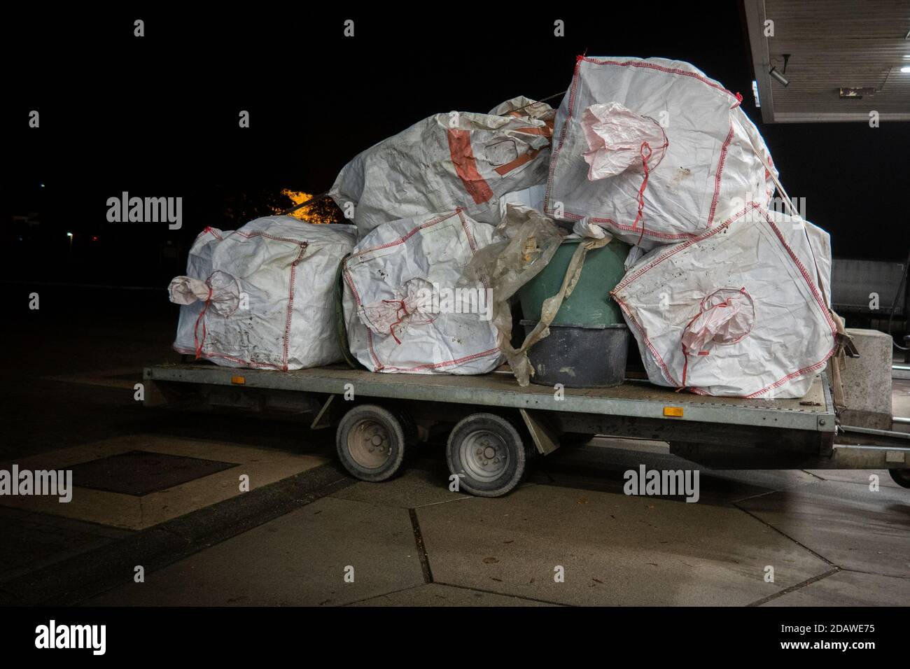 on a car trailer is a large load of white waste bags plastic garbage ...