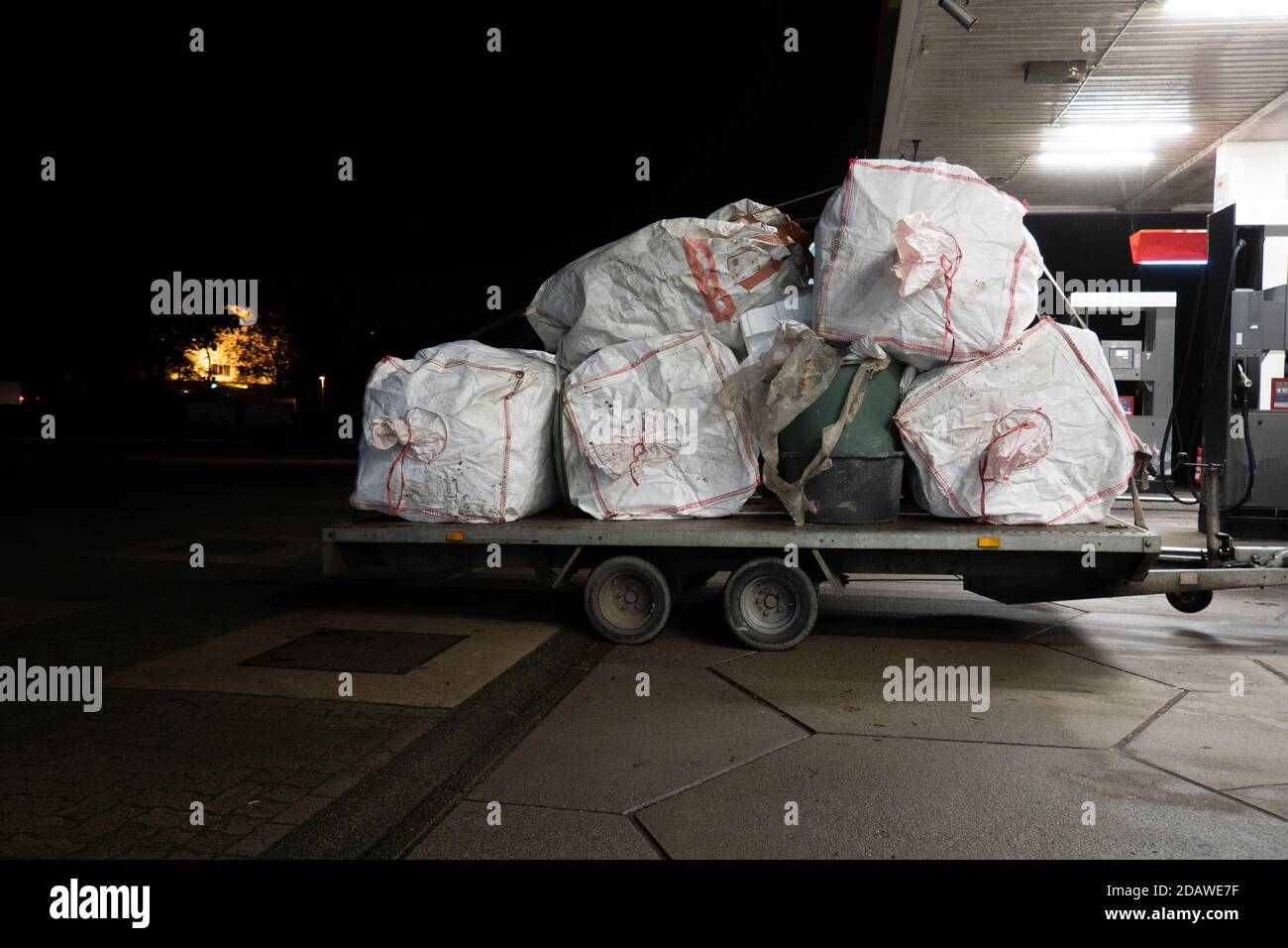 on a car trailer is a large load of white waste bags plastic garbage ...