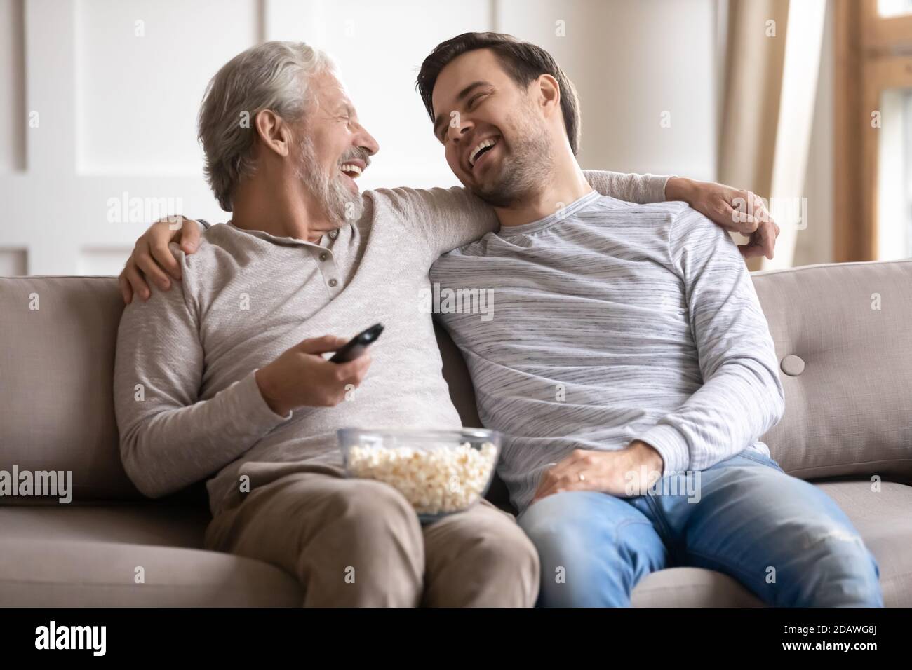 Happy older father with son hugging, watching tv at home Stock Photo ...