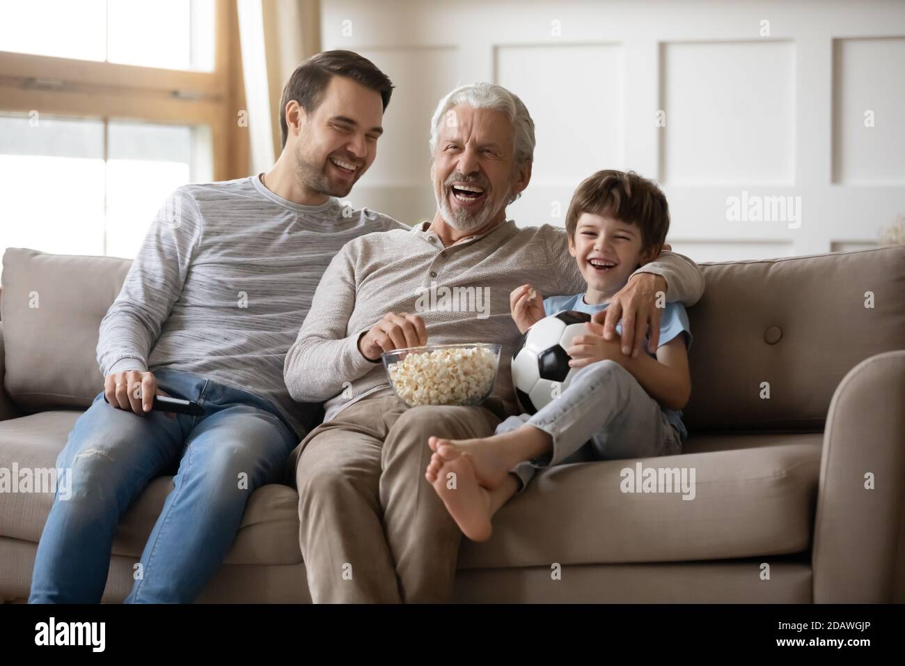 Happy little boy with grandfather and father watching tv Stock Photo ...