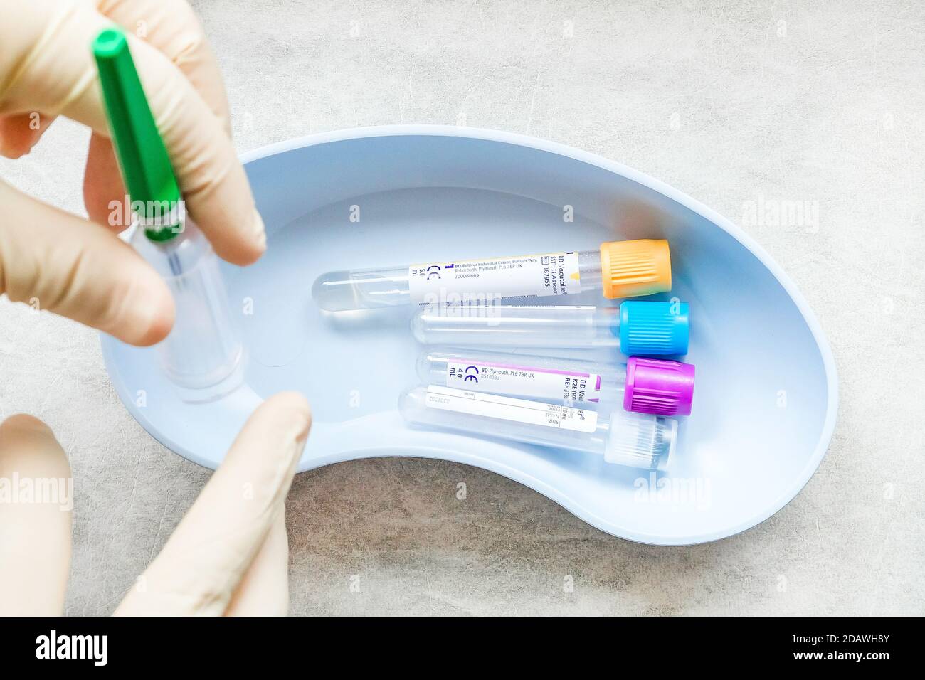 Colored test tubes are in a container. A gloved hand holds the device ...