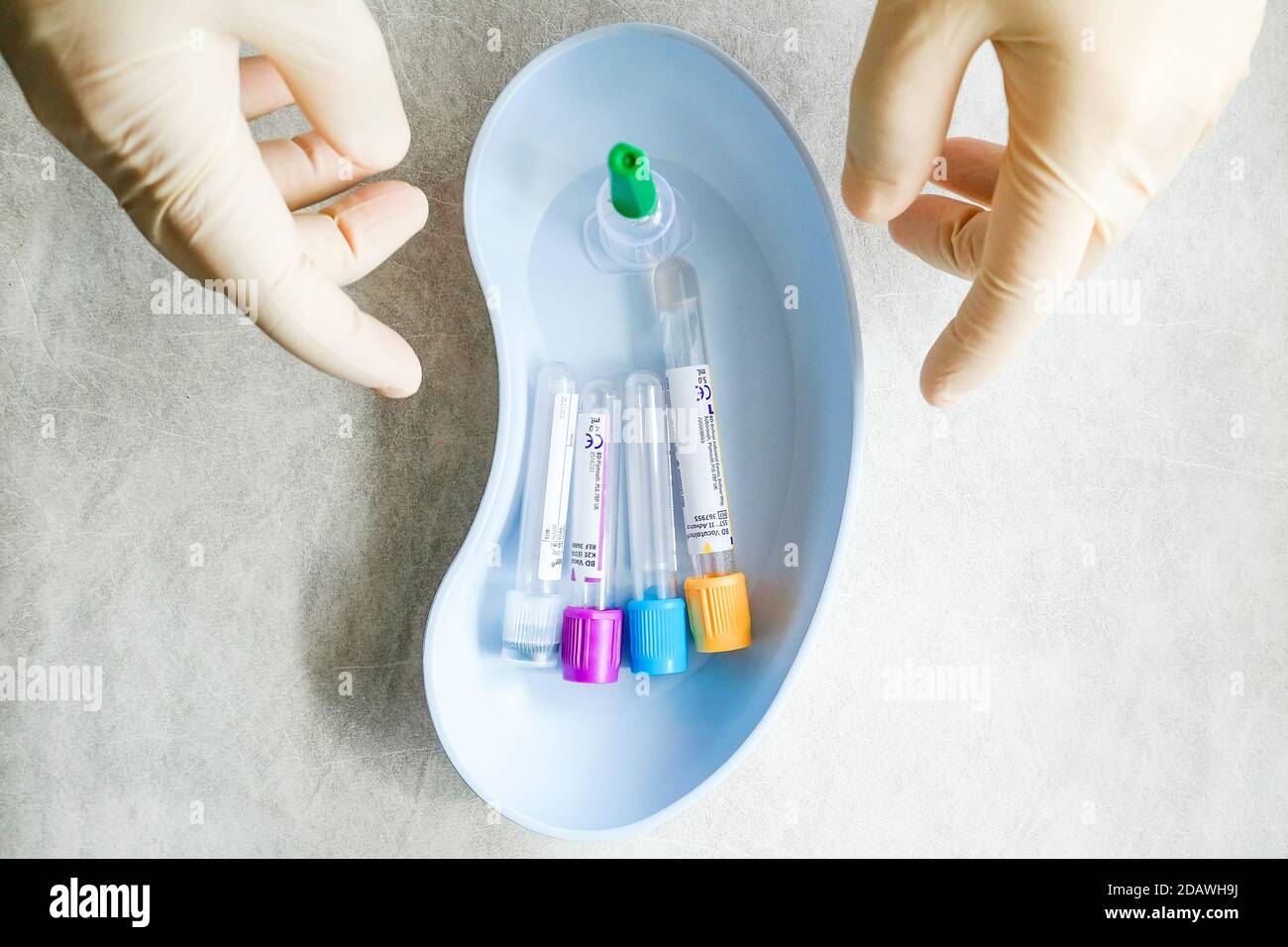 Colored test tubes are in a container. View from above. Hands with ...