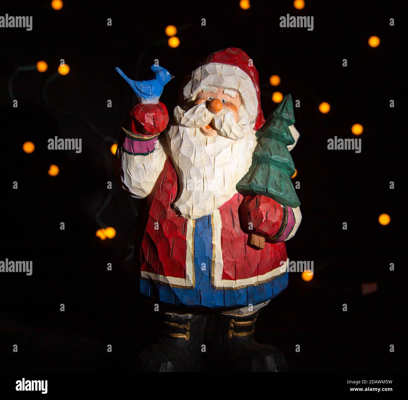 Santa clause figurine with blue bird on hand and a pine tree in the ...