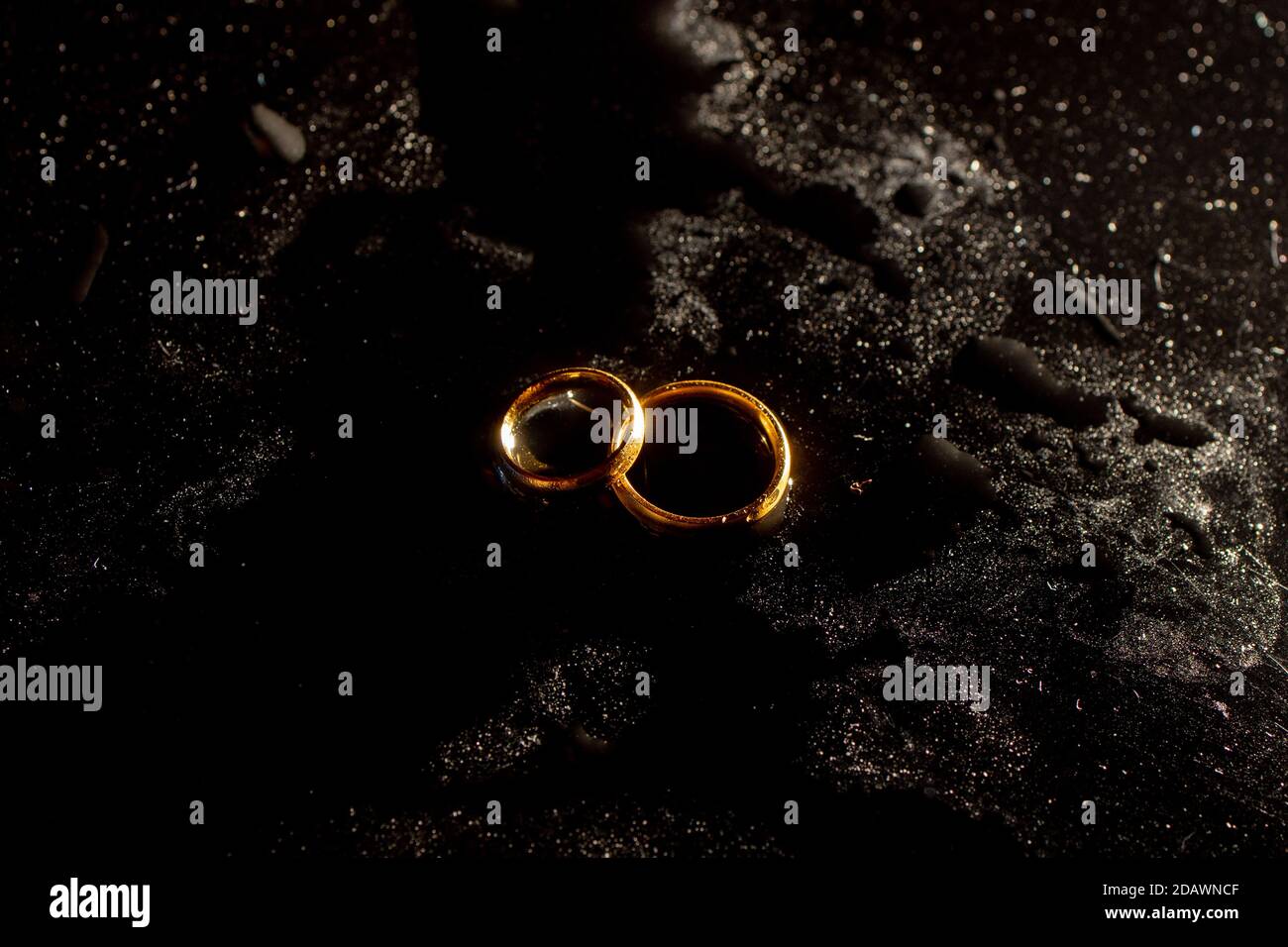 Two golden wedding rings on black background Stock Photo - Alamy
