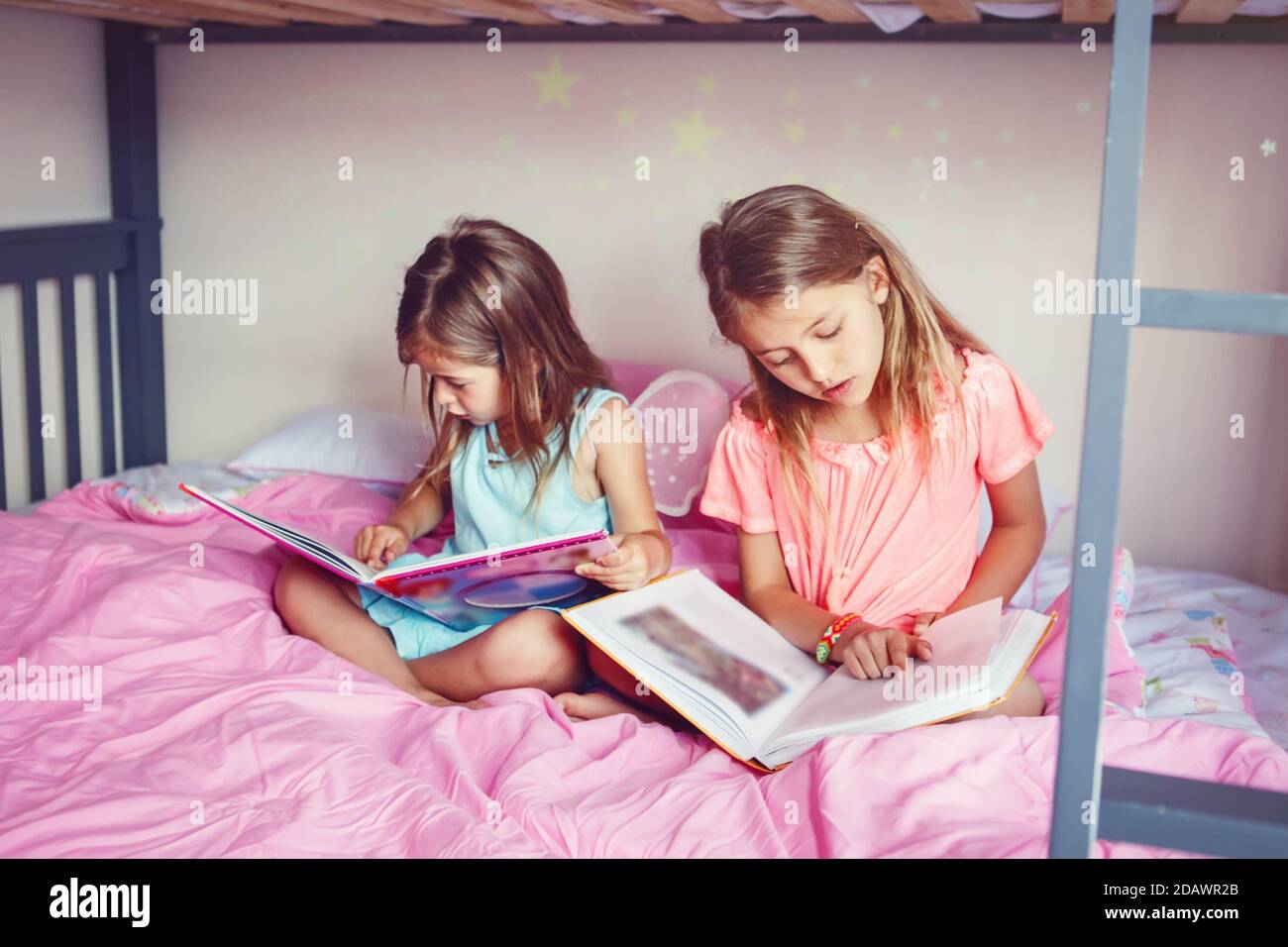 Happy Caucasian sisters girls reading books in bedroom. Children ...