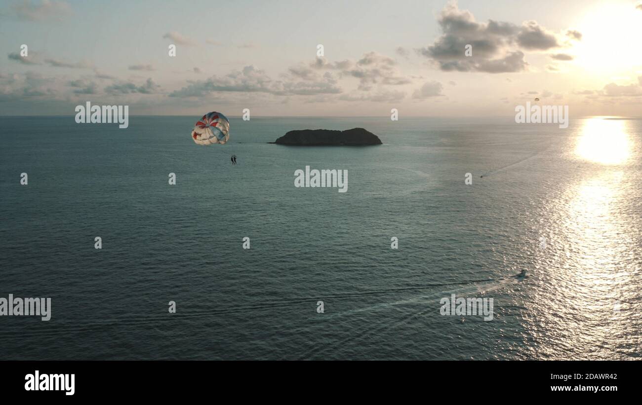Aerial shot of a parachute flying over calm reflective seawater under a ...