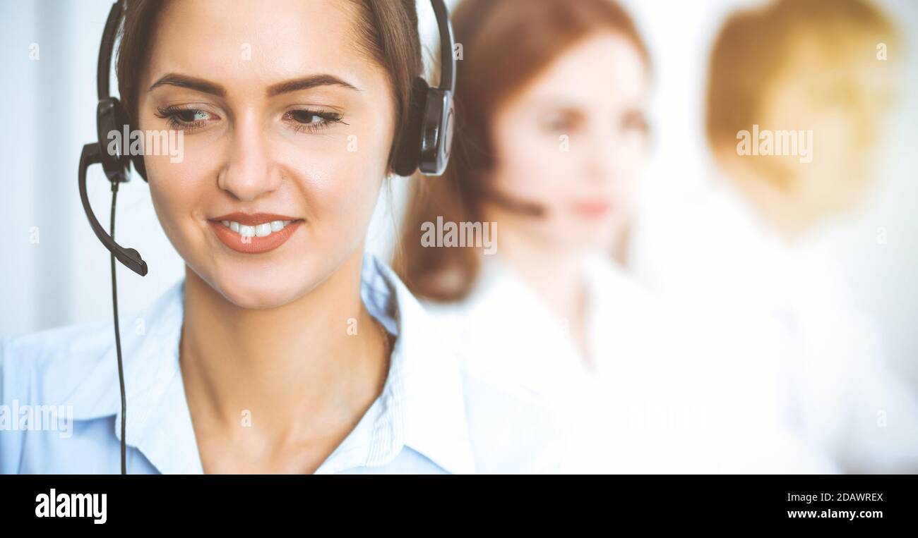 Call center operators. Focus on beautiful business woman in headset ...