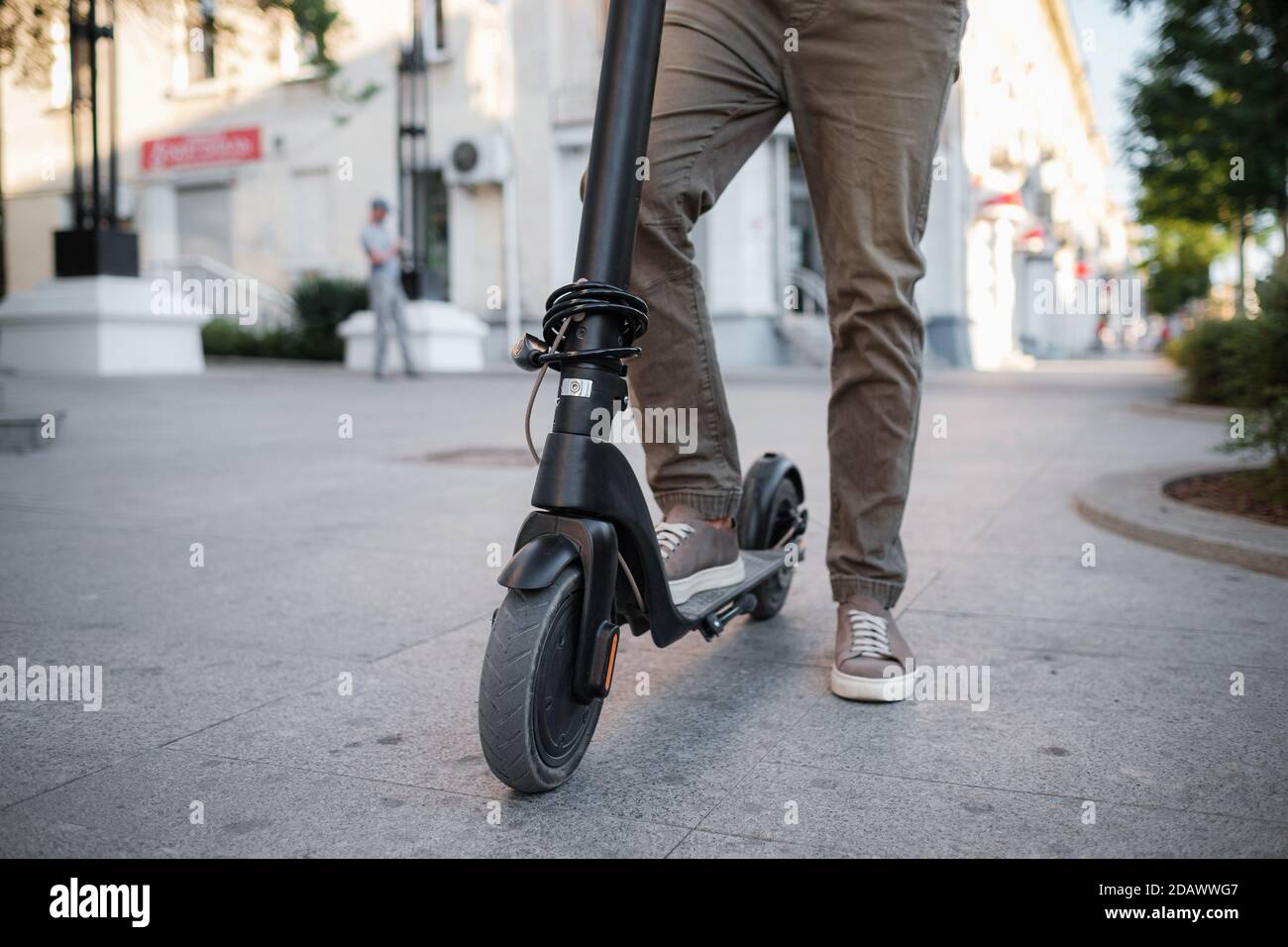 Close up of man riding black electric kick scooter at cityscape at ...
