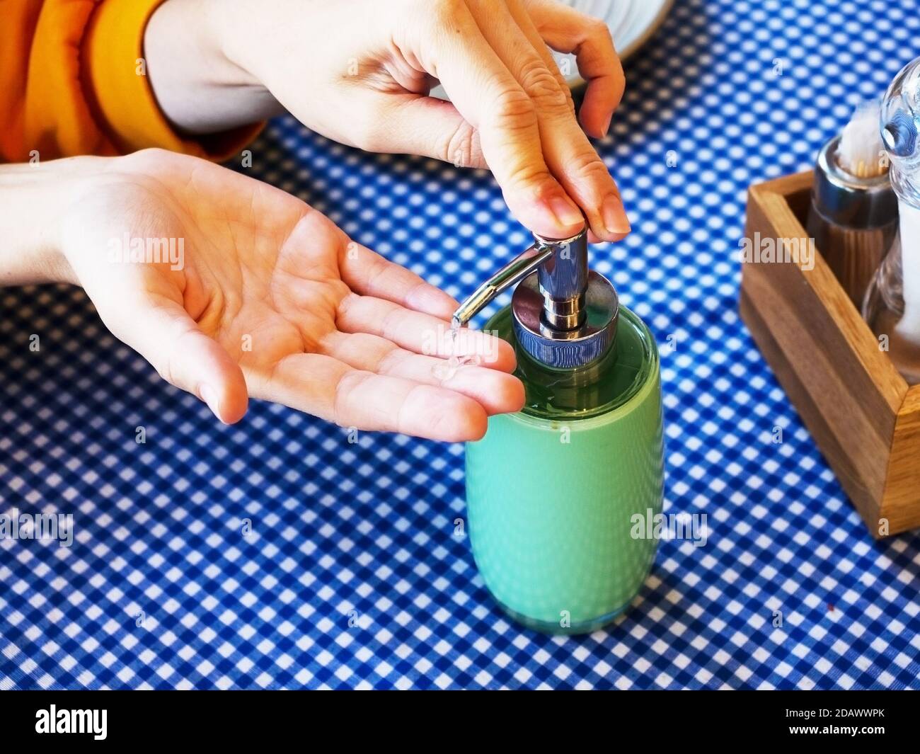 Female hands squeeze transparent gel antiseptic from a pump standing on ...