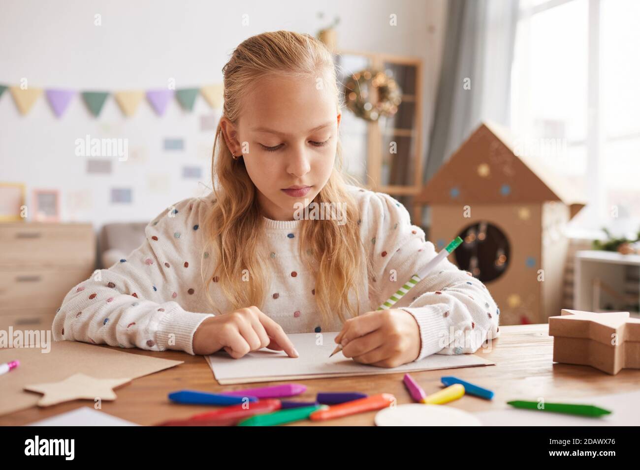 Front view portrait of blonde teenage girl drawing or doing homework ...