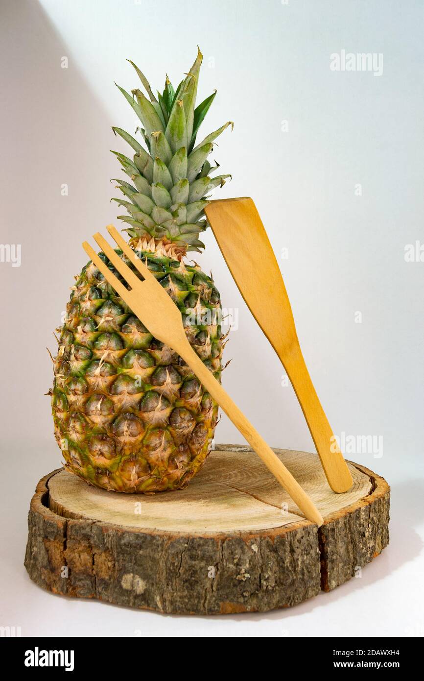 Fresh whole pineapple resting on a log with a white background and a ...
