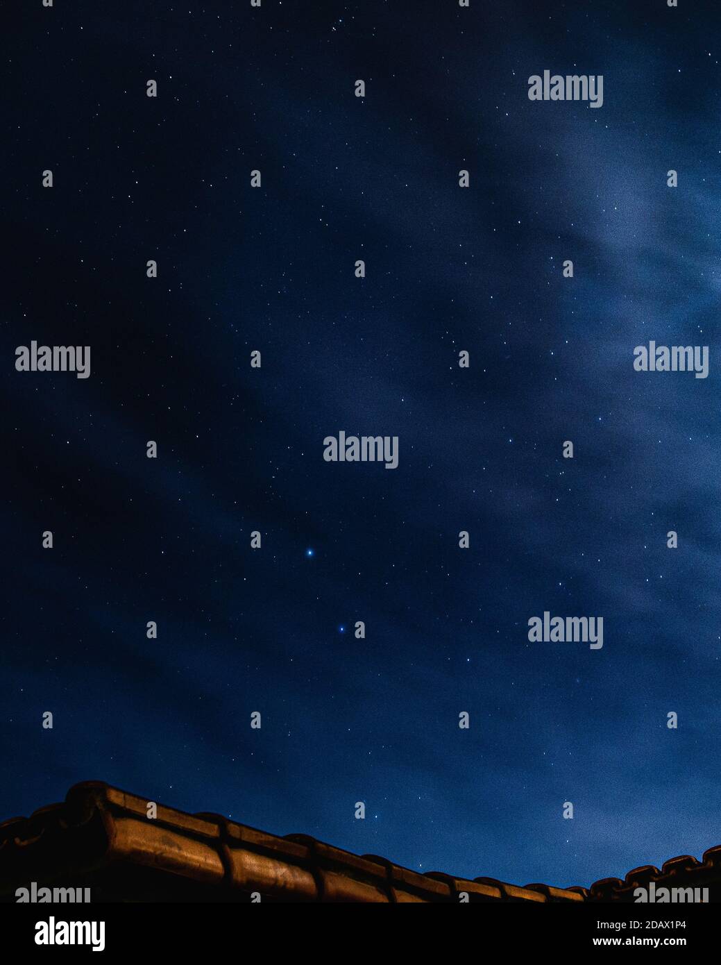 Vertical shot of a tiled rural building roof under a beautiful starry ...