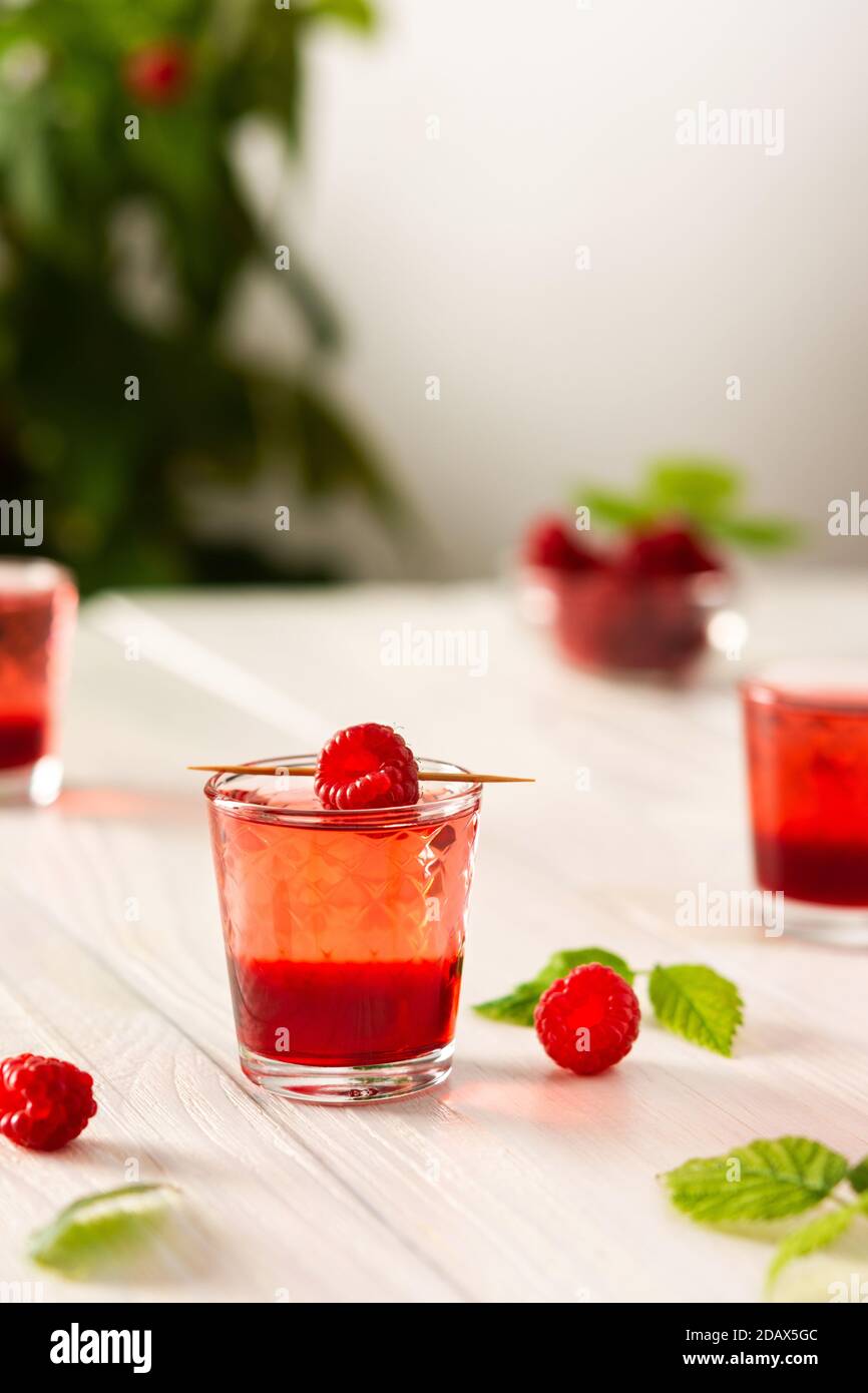 Raspberry alcoholic shots, shot glasses with colored liquor on a white ...