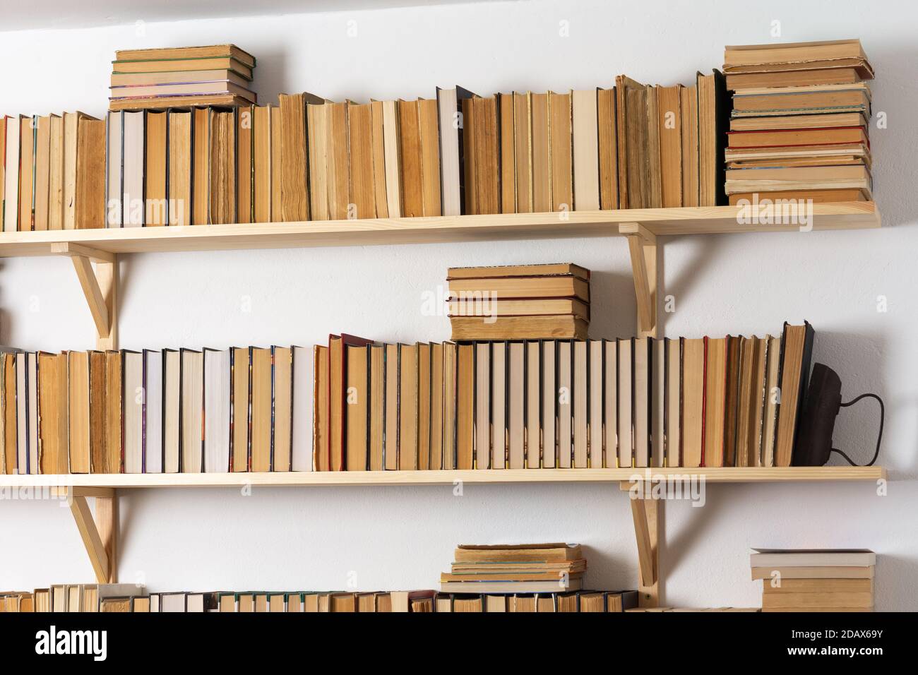Light wooden bookshelves with hardback overturned books in white ...