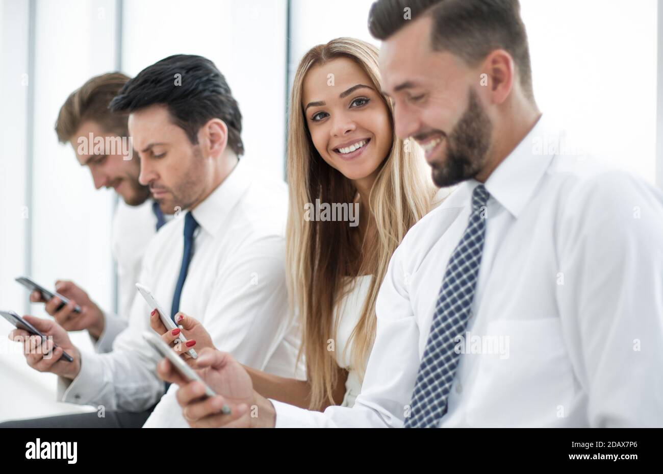 business colleagues using out smartphones sitting in the office waiting room Stock Photo - Alamy