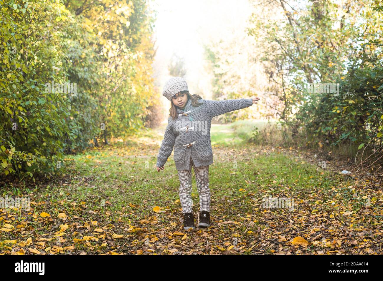 Cute little girl flying with open arms like a plane in the autumn sunny ...