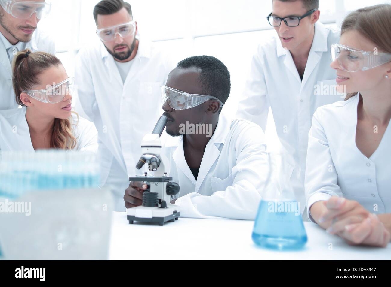 Focused and serious female and male chemists in lab coats and safety ...