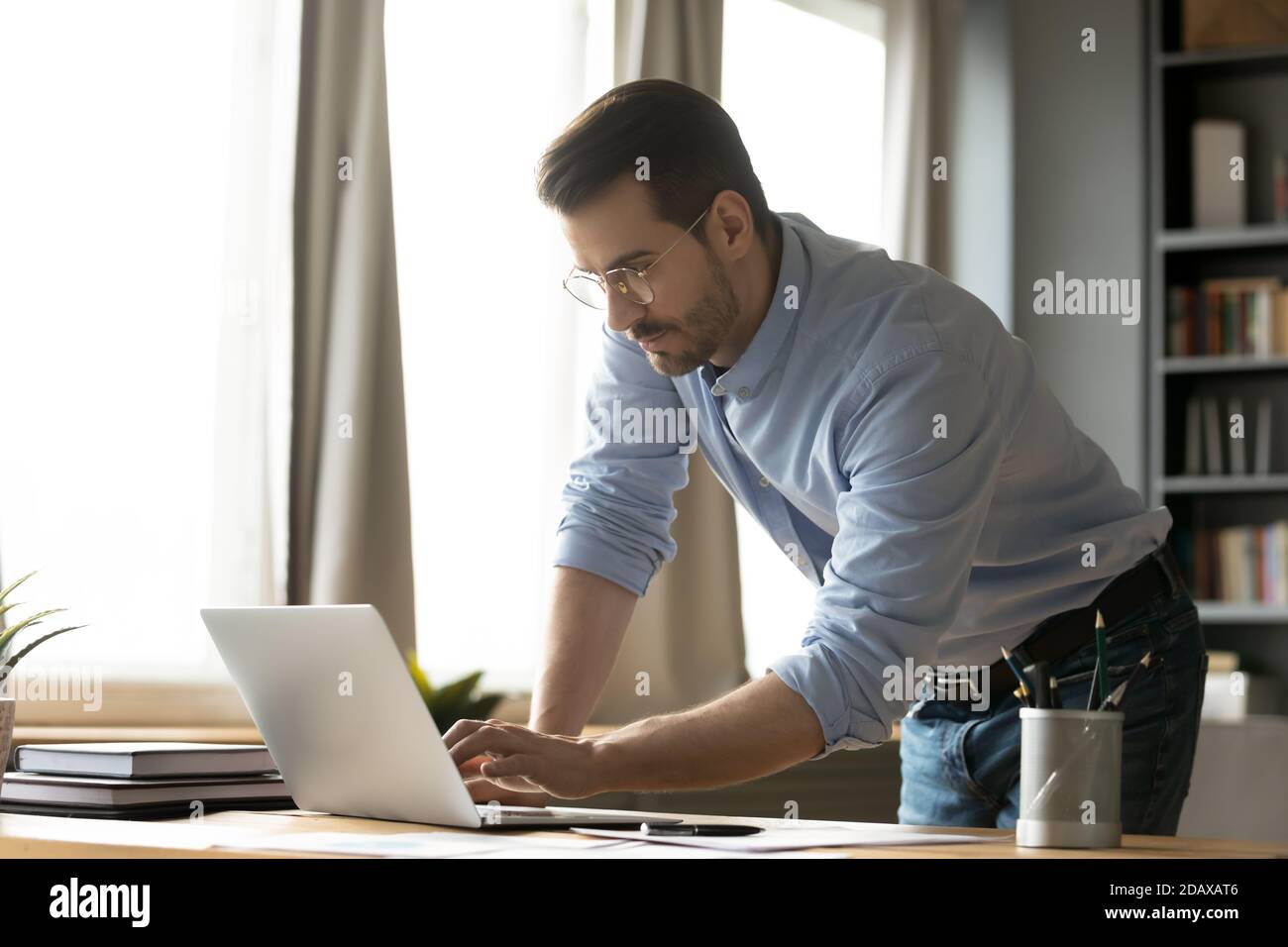 Businessman standing lean over workplace desk working on wireless ...