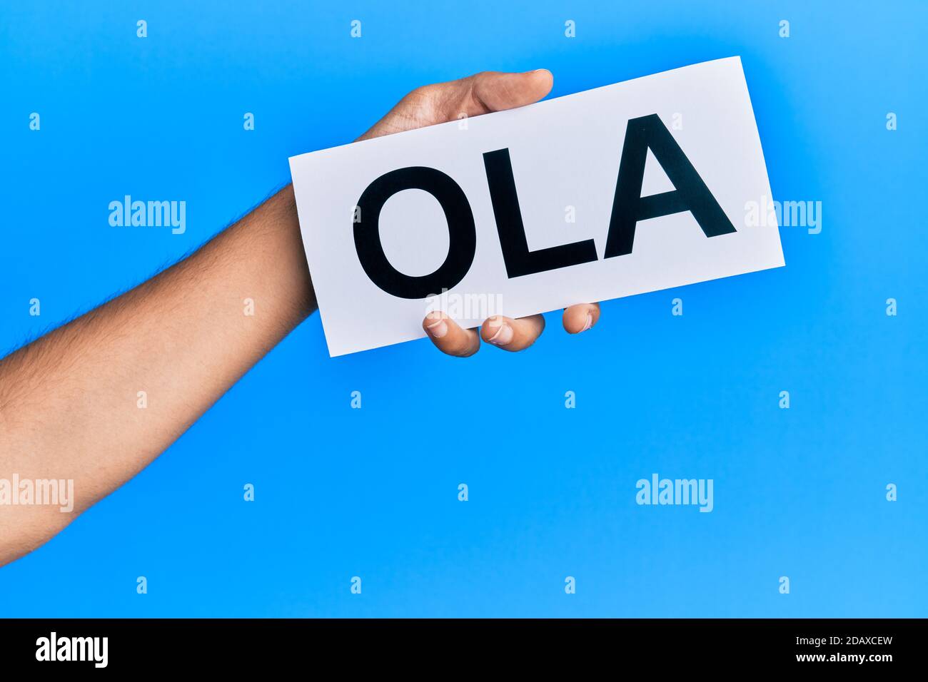 Hand of hispanic man holding ola word paper over isolated blue ...