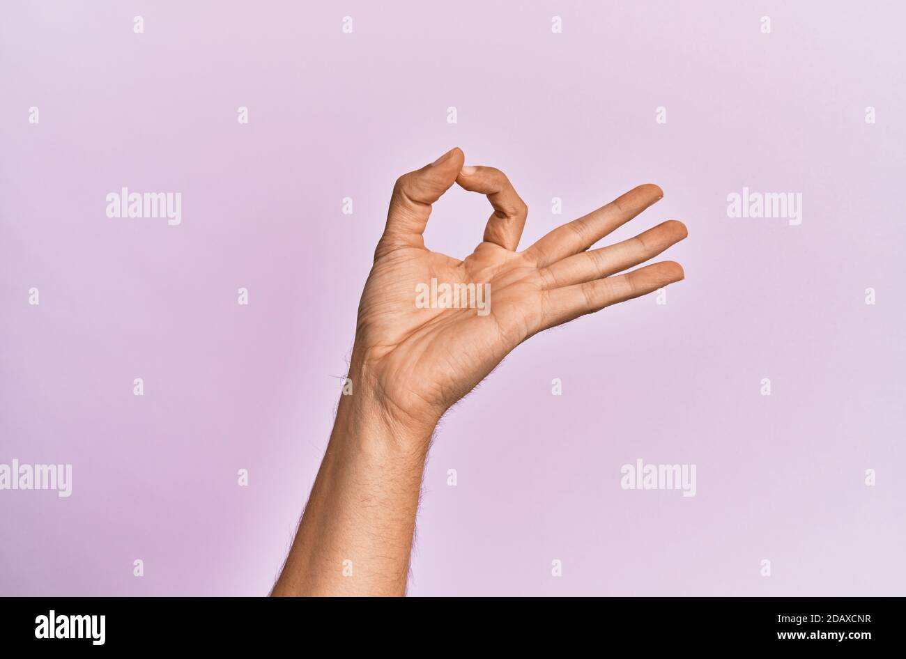 Arm and hand of caucasian young man over pink isolated background ...