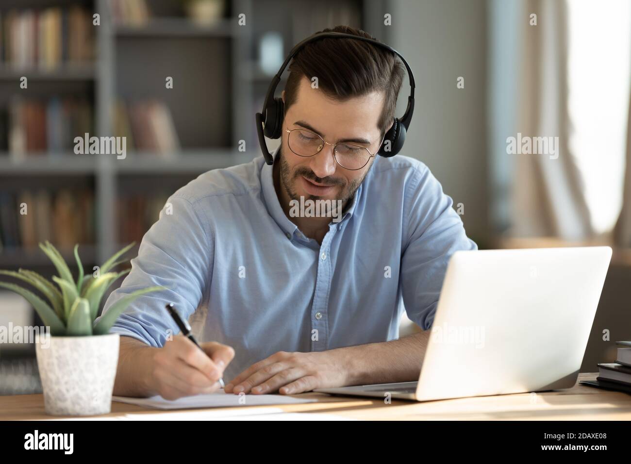 Man Wear Headphones Watch Webinar Using Laptop Writing Notes Stock