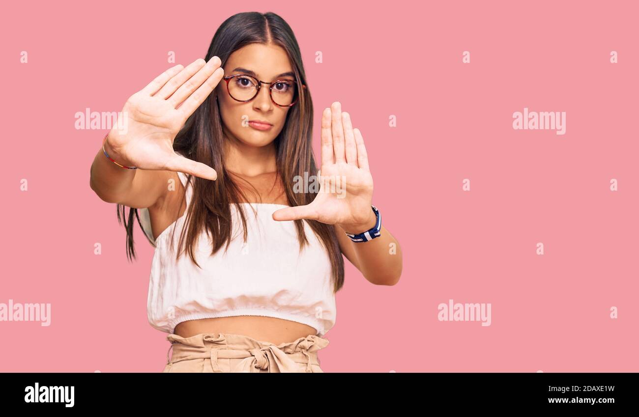 Young hispanic woman wearing casual clothes and glasses doing frame ...