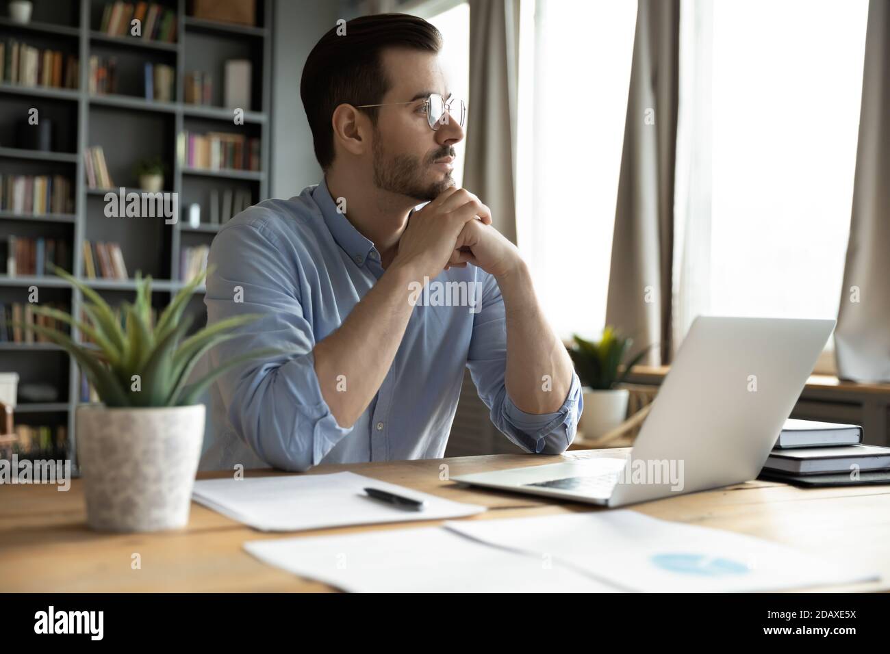 Pensive businessman sits at workplace desk look out the window Stock ...