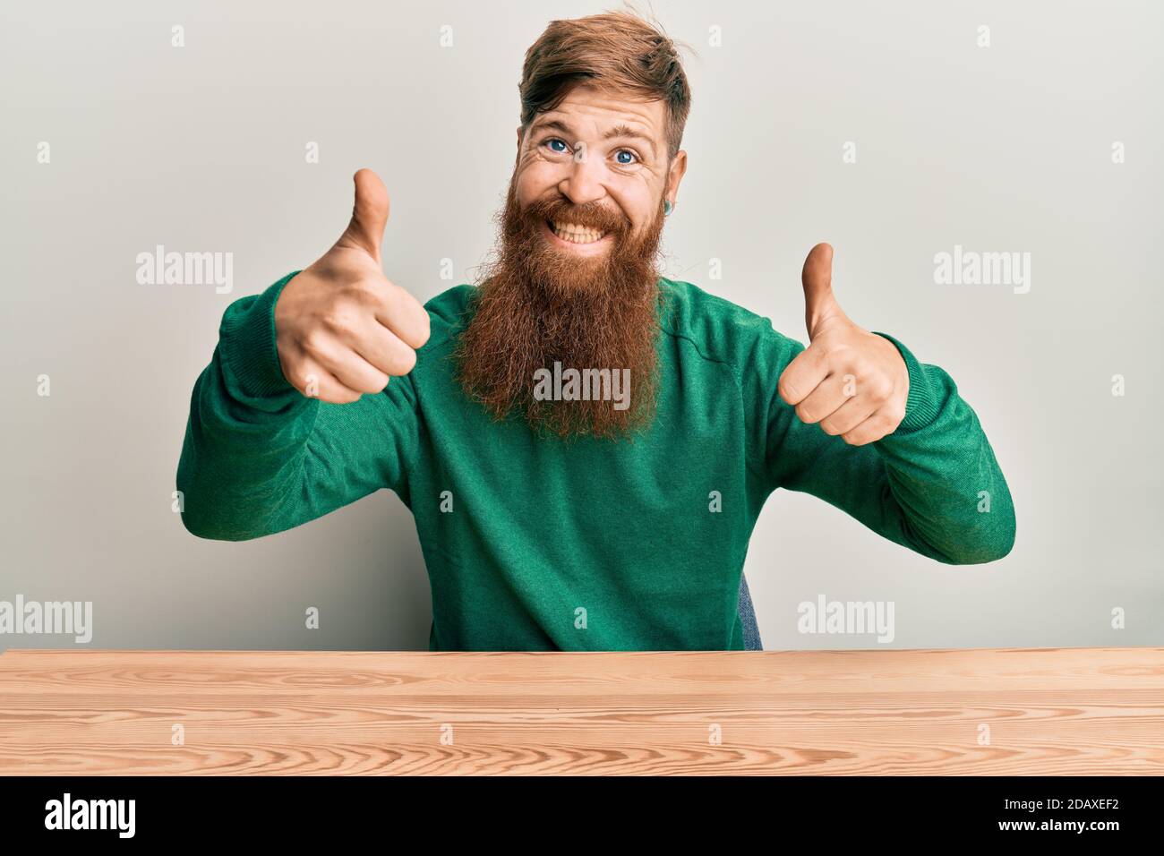 Young irish redhead man wearing casual clothes sitting on the table ...