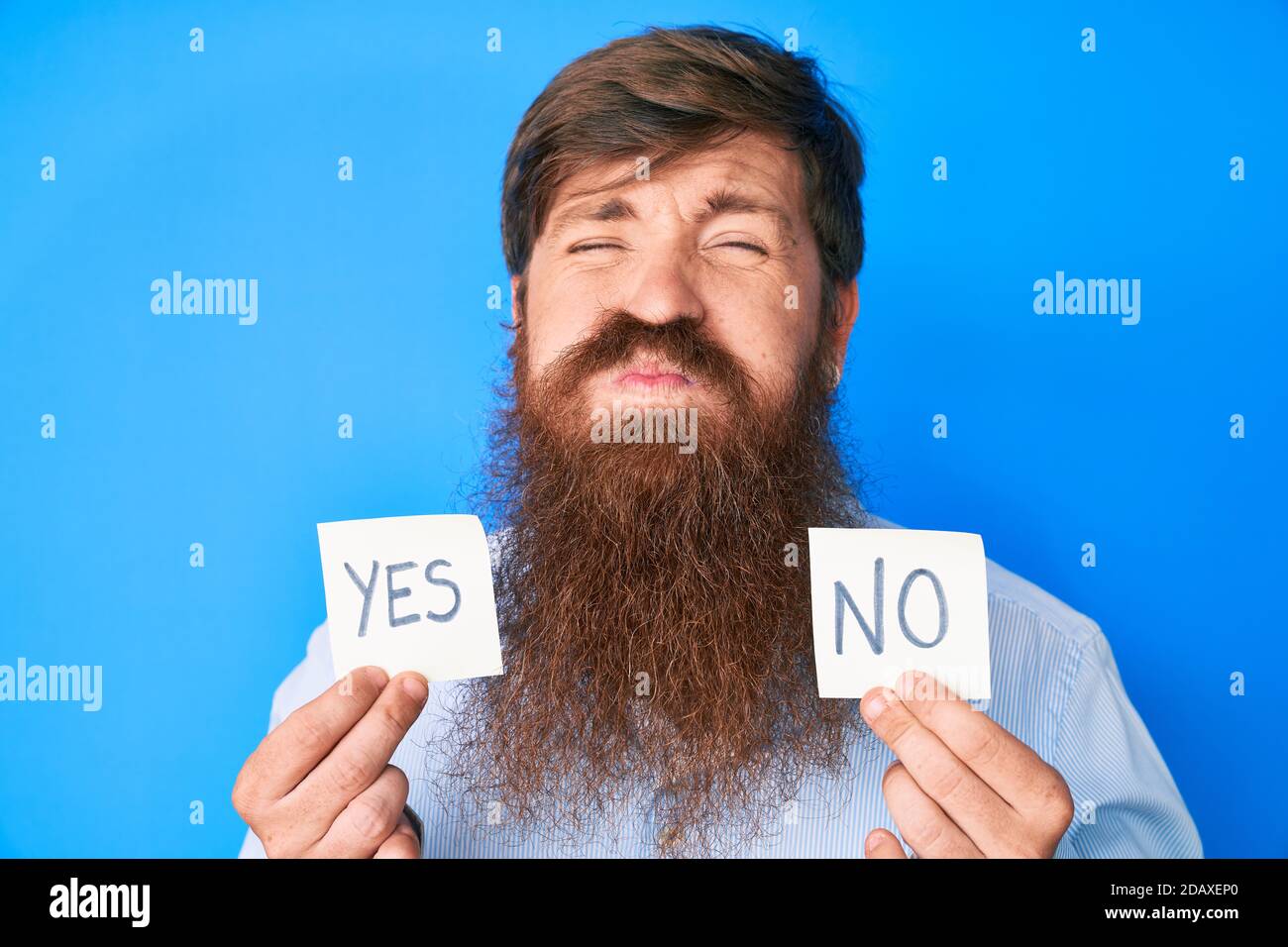 Handsome young red head man with long beard holding yes and no reminder ...