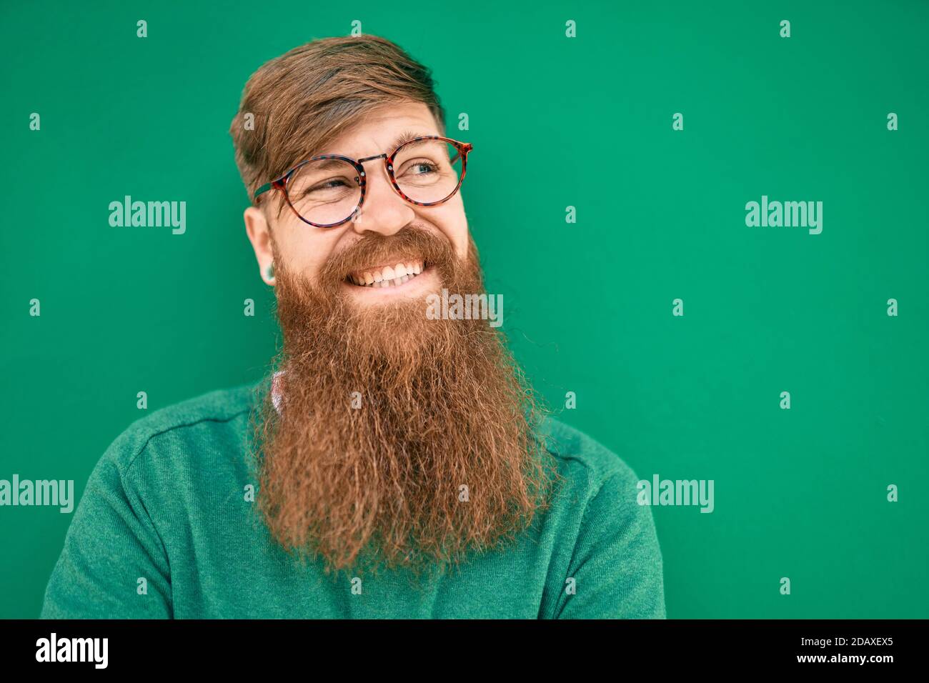 Young irish man with redhead beard smiling happy leaning on the wall at ...
