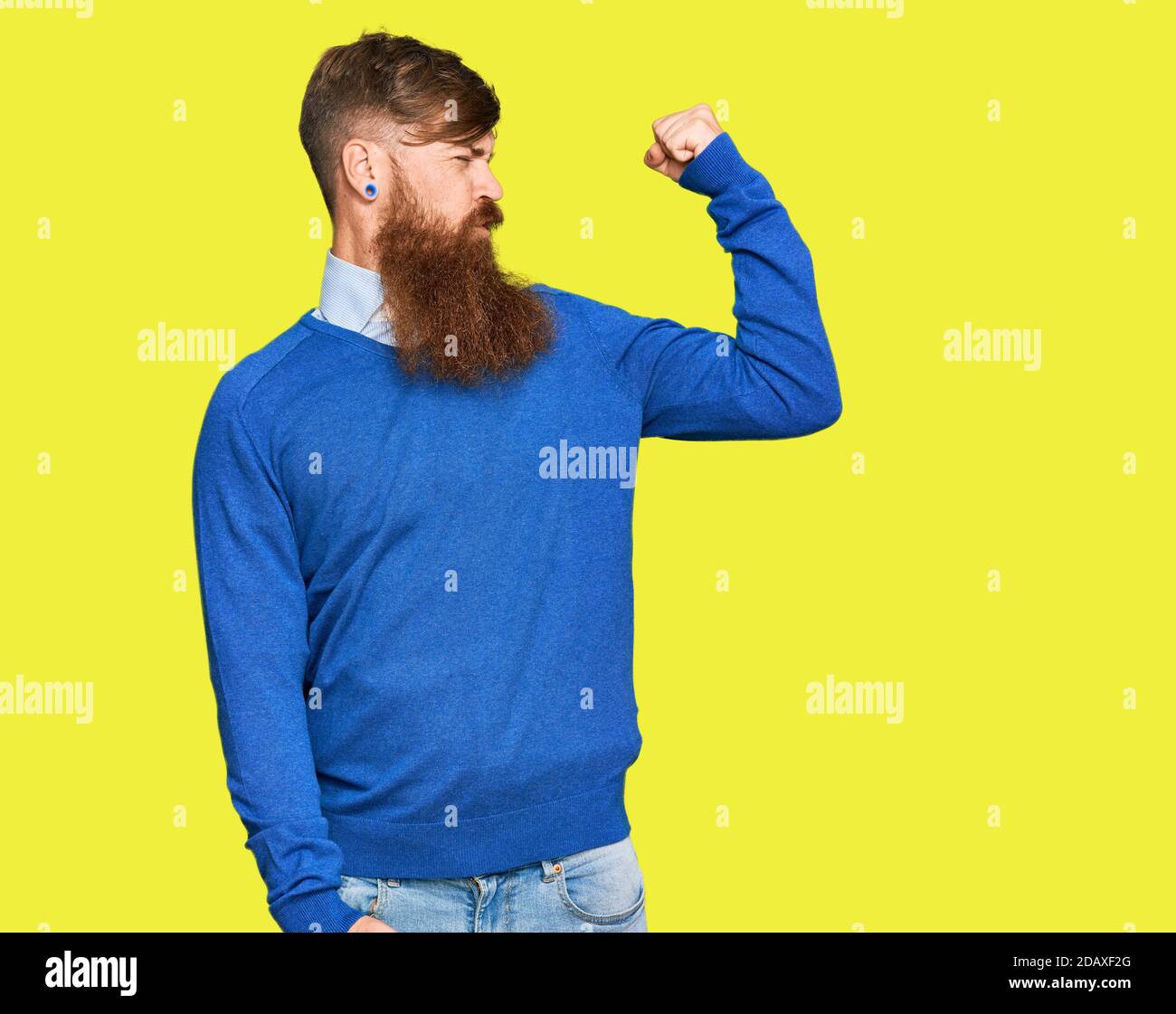 Young irish redhead man wearing casual clothes showing arms muscles ...