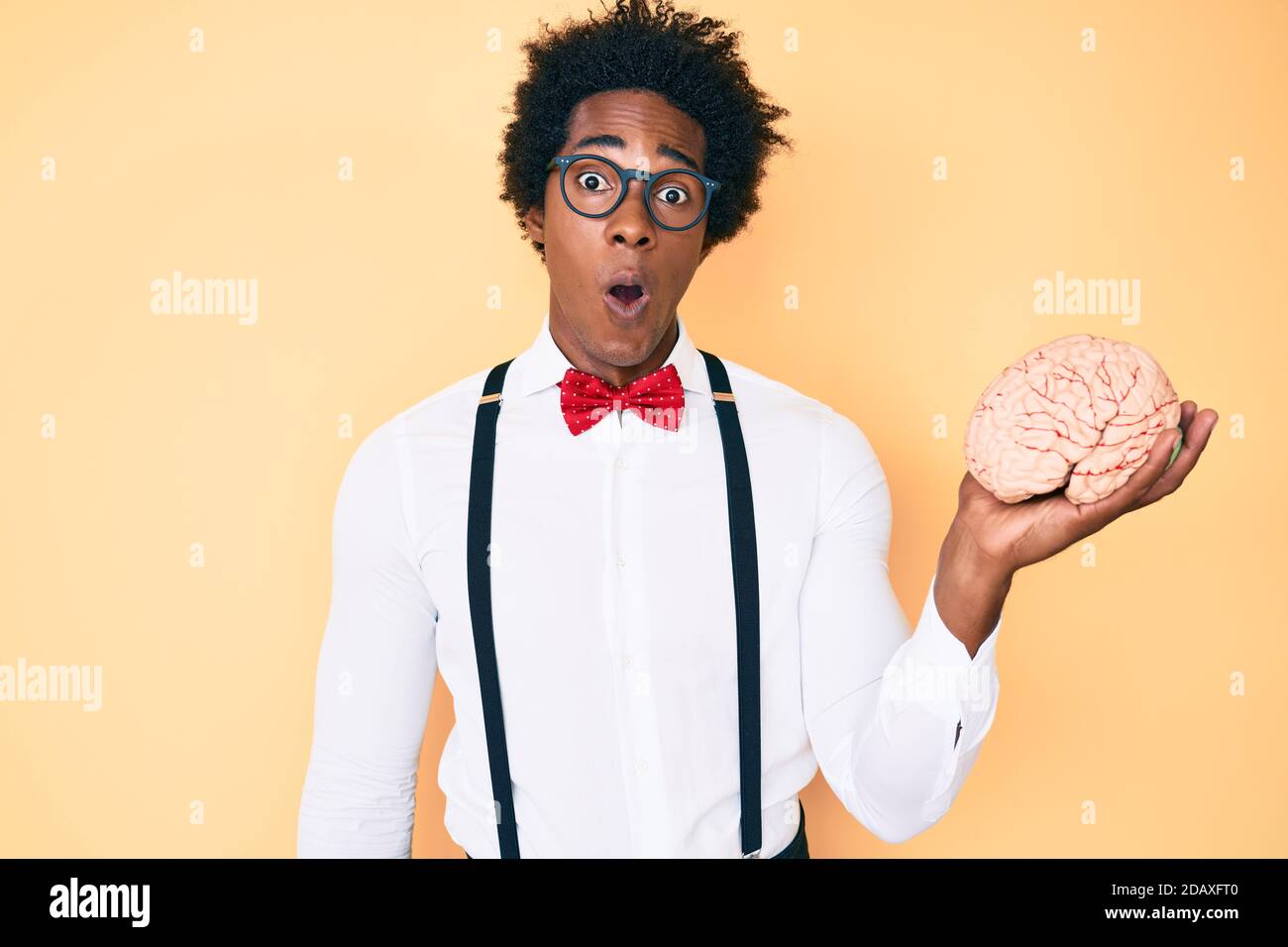 Handsome african american nerd man with afro hair holding brain scared ...