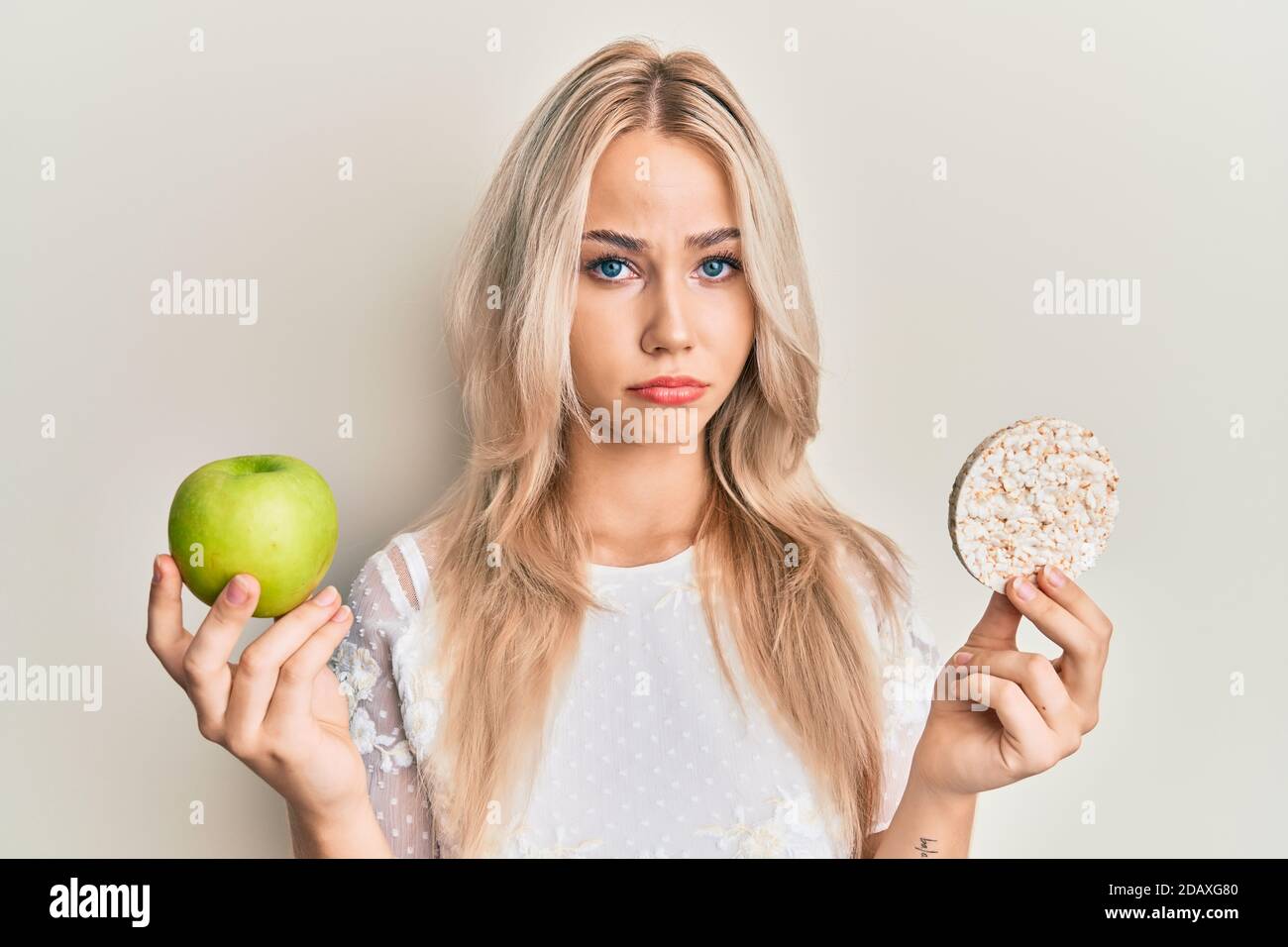 Beautiful caucasian blonde girl holding nachos and healthy green apple ...
