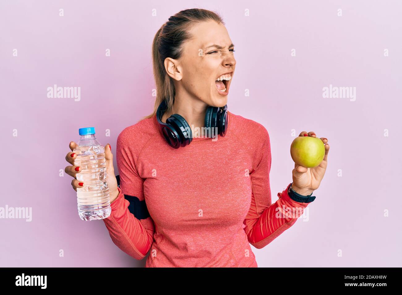 Beautiful caucasian sports woman holding water bottle and green apple ...