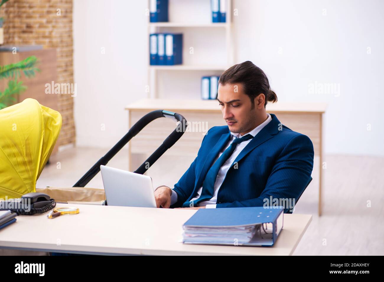 Young employee looking after kid at workplace Stock Photo - Alamy