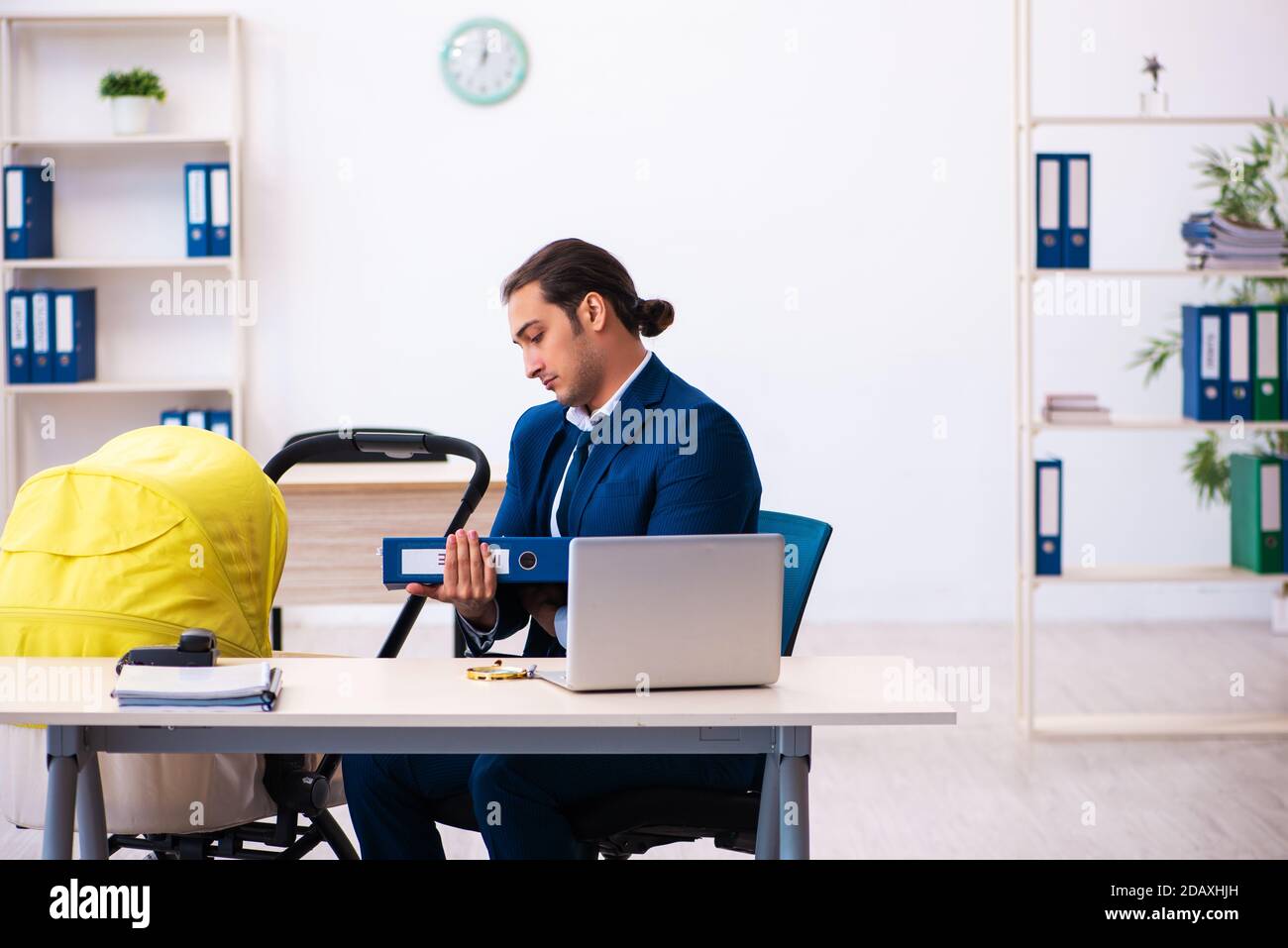 Young employee looking after kid at workplace Stock Photo - Alamy