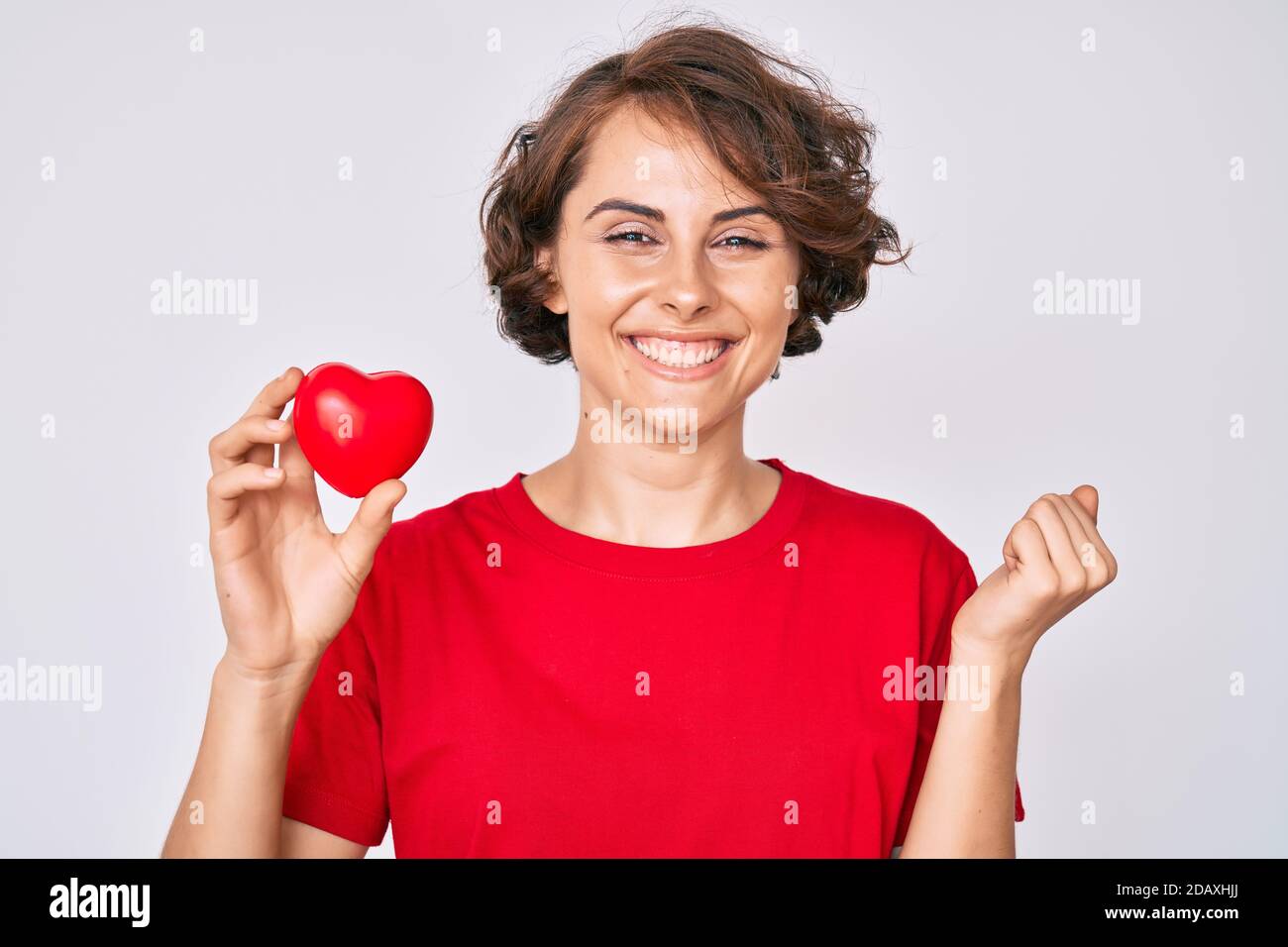 Young hispanic woman holding heart screaming proud, celebrating victory ...