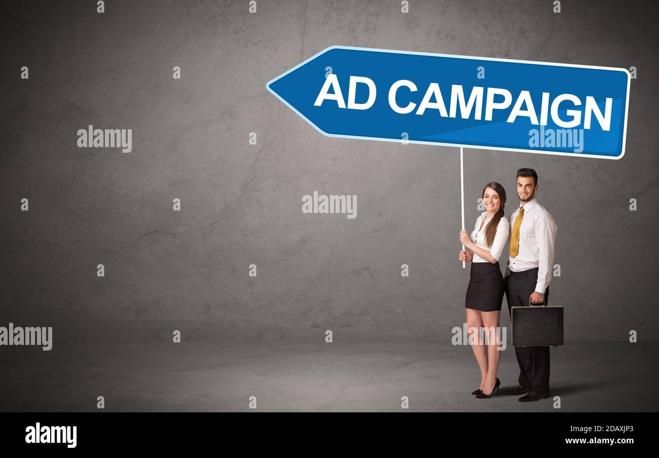 Young business person in casual holding road sign with AD CAMPAIGN ...